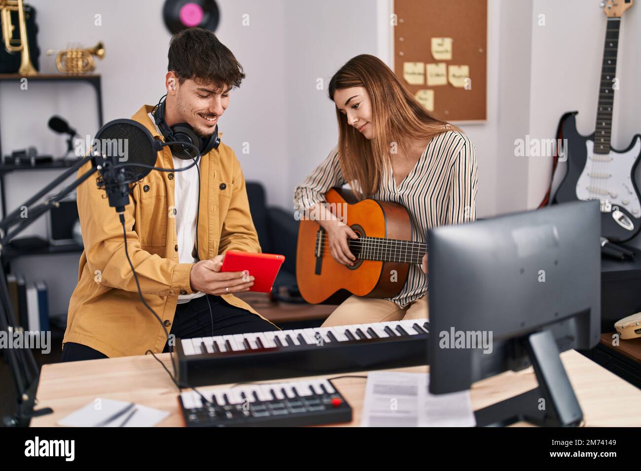 Mand and woman musicians playing classical guitar using touchpad at ...