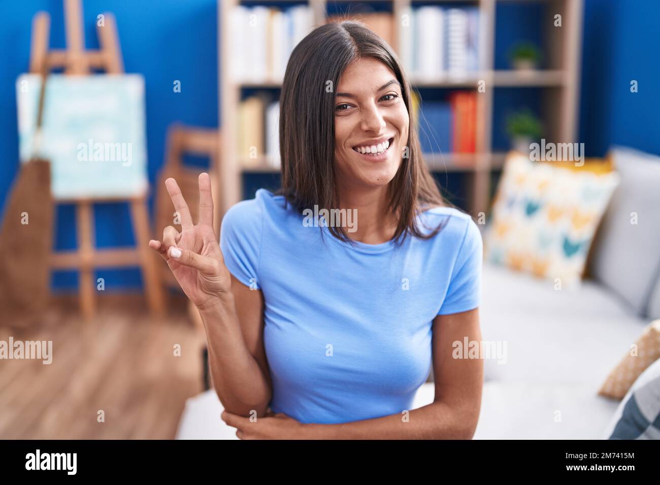 Brunette young woman sitting on the sofa at home smiling with happy ...