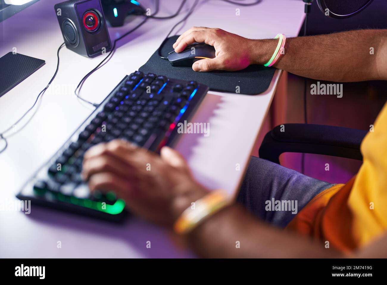 Young hispanic man using computer keyboard and mouse at gaming room ...