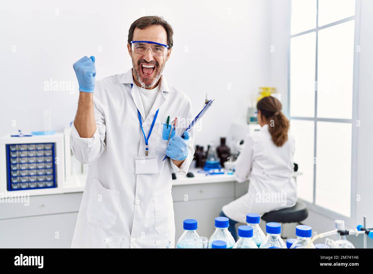 Middle age man working at scientist laboratory screaming proud ...