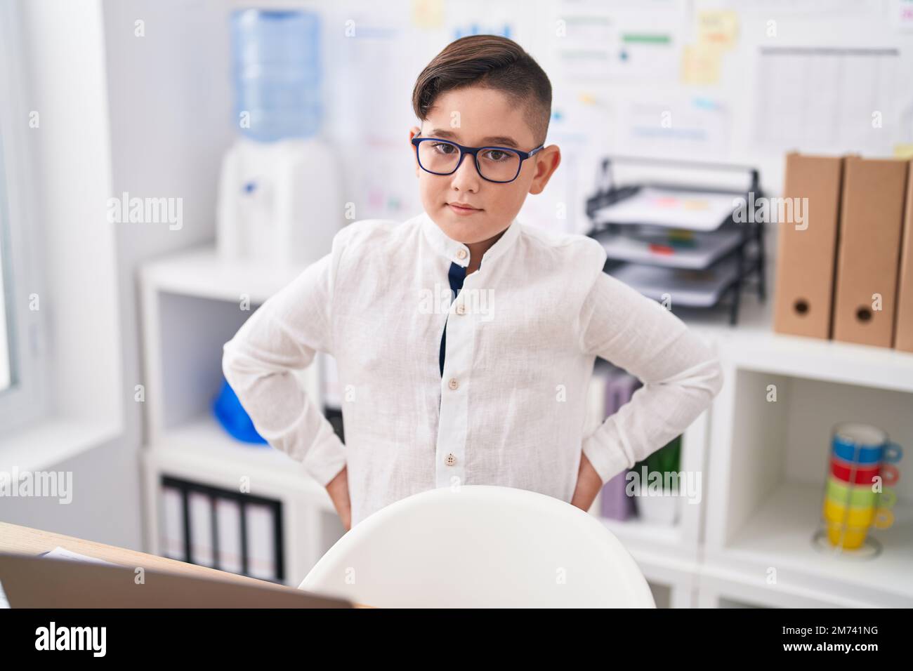 Adorable hispanic boy business worker standing with serious expression ...