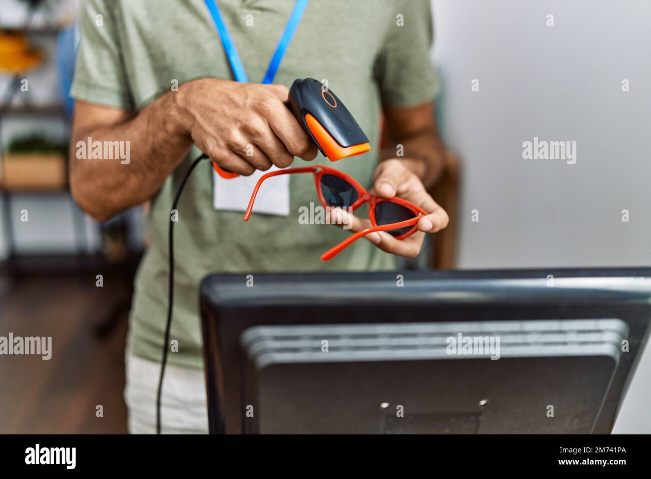 Handsome hispanic man working at shop using barcode scanner at retail ...