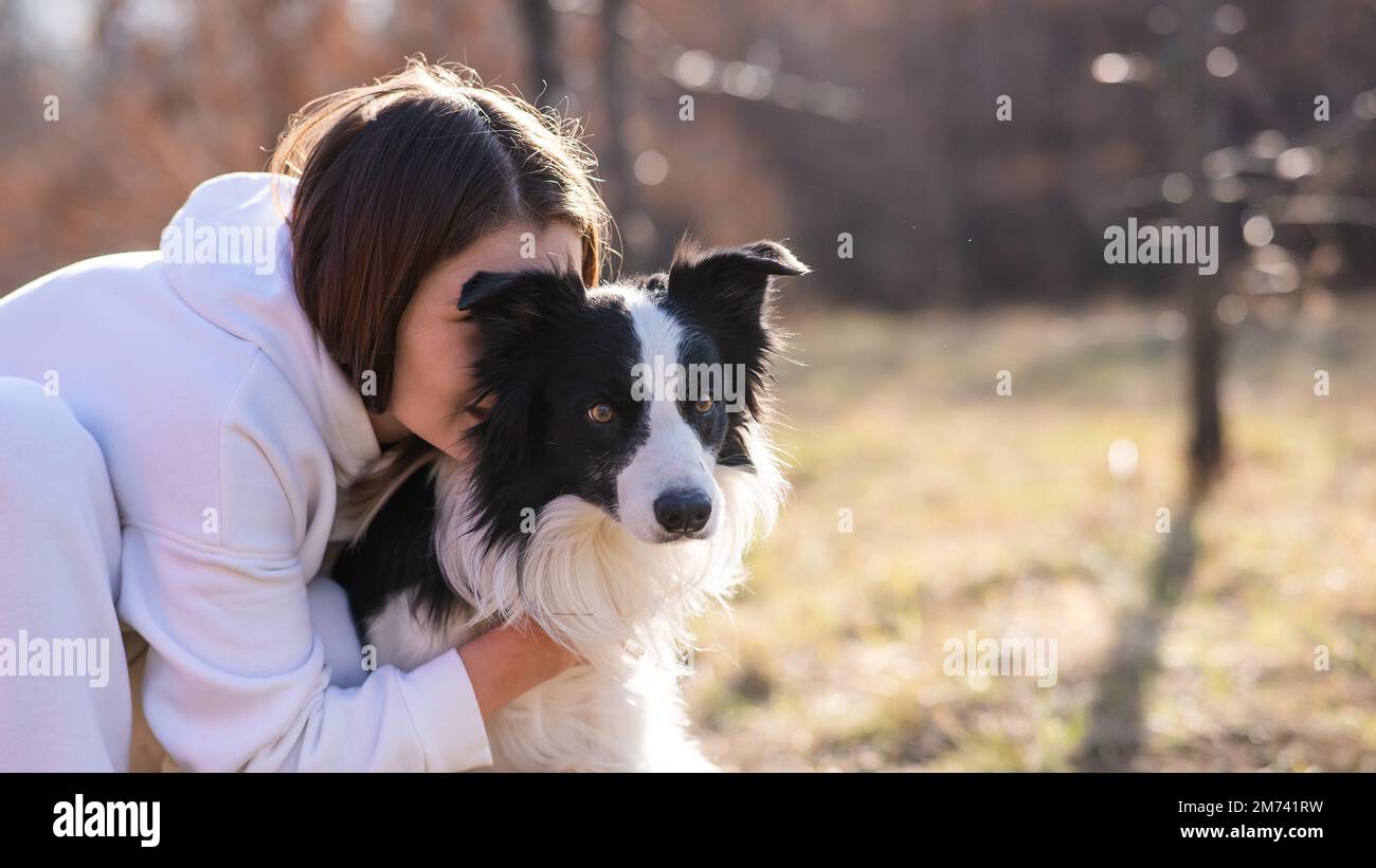Caucasian woman hugging her dog Border Collie while sitting on a bench ...