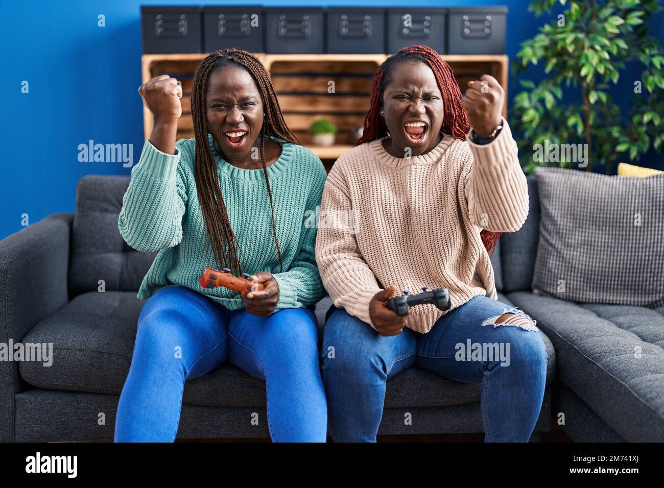 Two african woman playing video game holding controller annoyed and ...