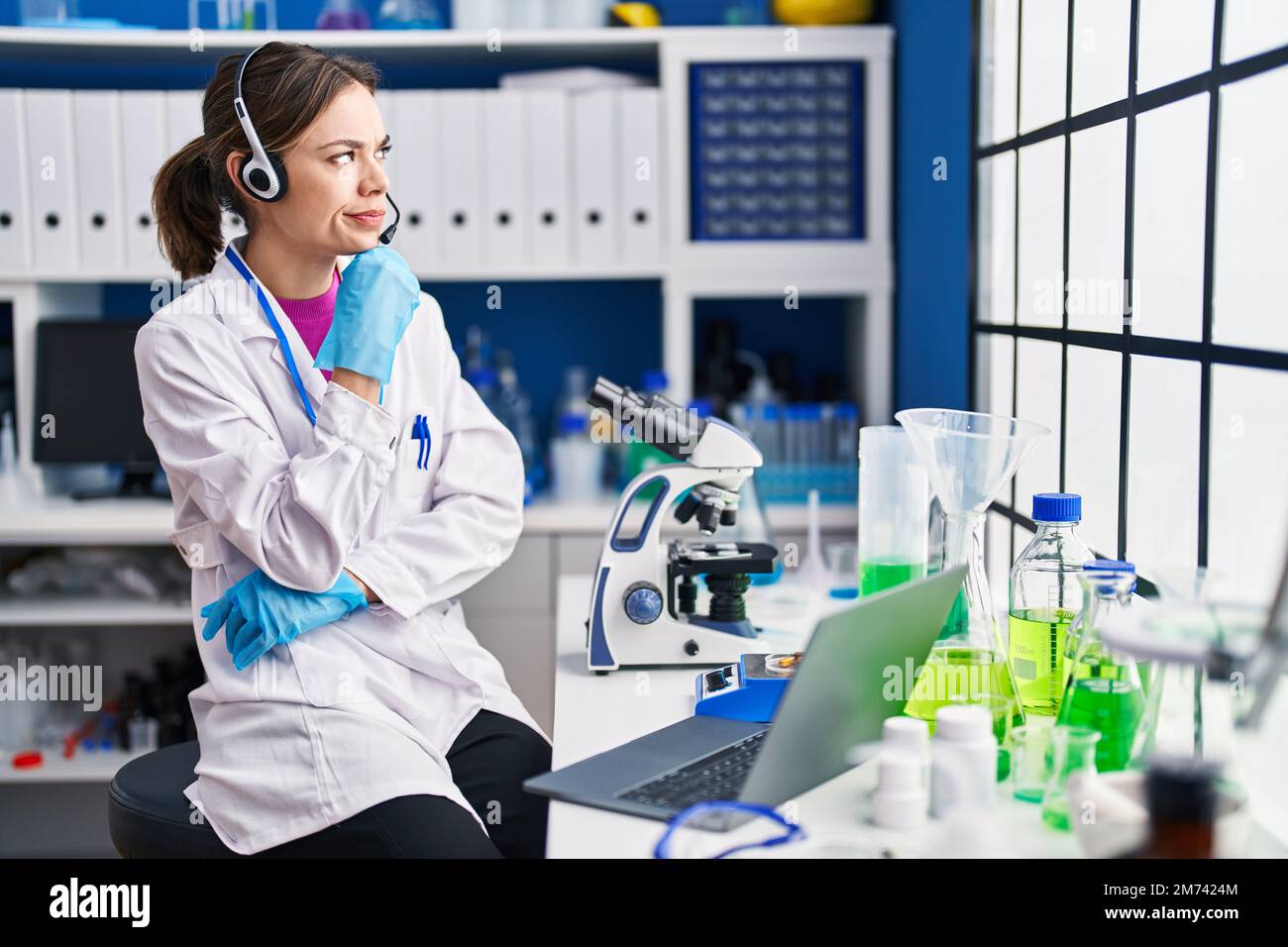 Hispanic woman working at scientist laboratory serious face thinking ...
