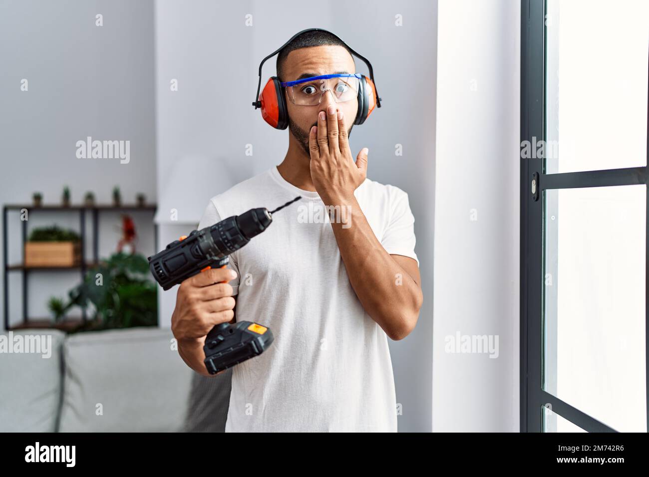African american man holding screwdriver wearing ear protection at home ...