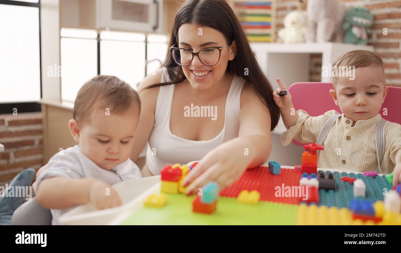 Teacher and preschool students playing with construction blocks sitting ...