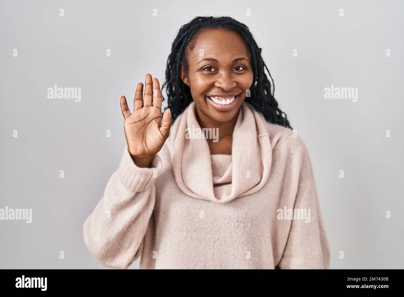 African woman standing over white background waiving saying hello happy ...
