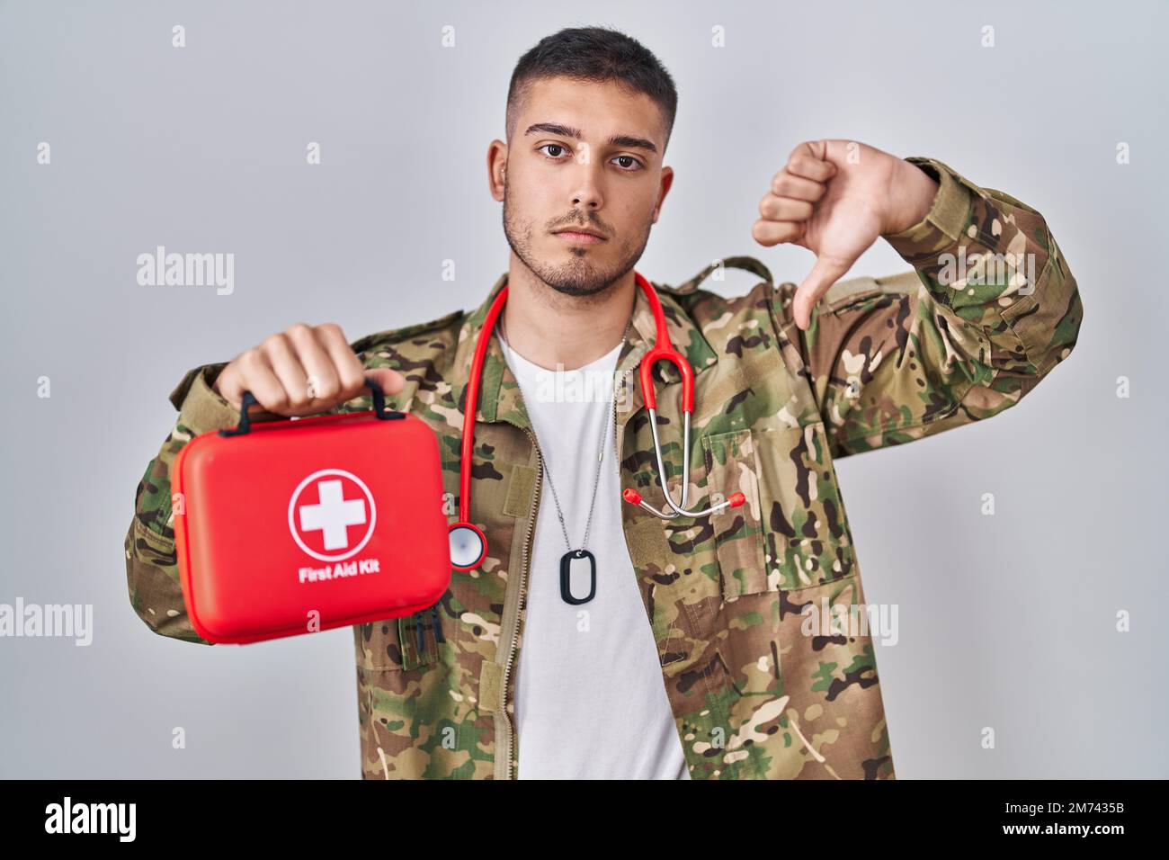 Young hispanic doctor wearing camouflage army uniform holding first aid ...