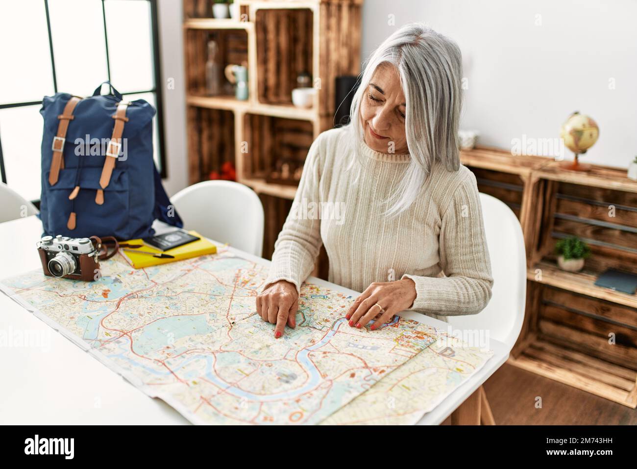 Middle age grey-haired woman smiling confident preparing travel at home ...