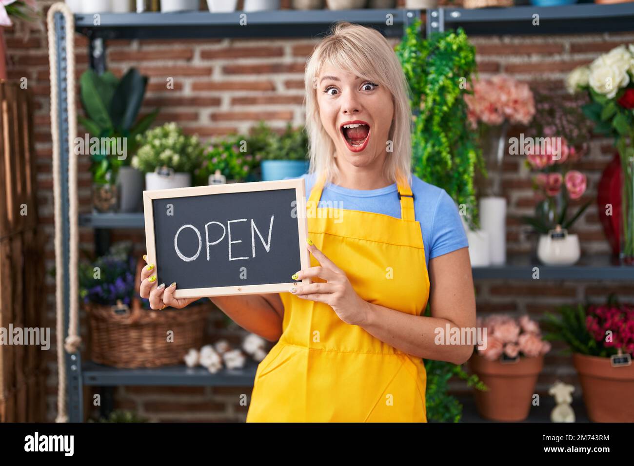 Young caucasian woman working at florist holding open sign celebrating ...