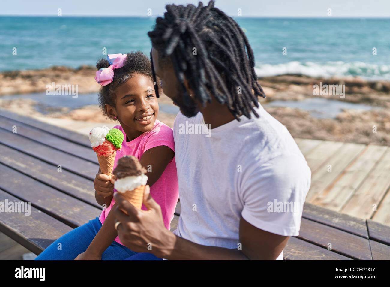 Father And Daughter Eating Ice Cream Sitting Together On Bench At