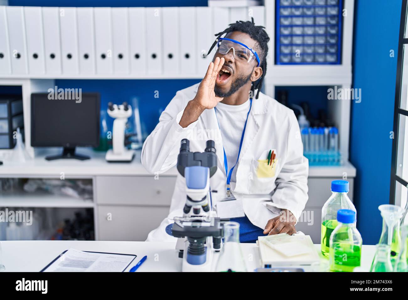 African man with dreadlocks working at scientist laboratory clueless and confused with open arms ...