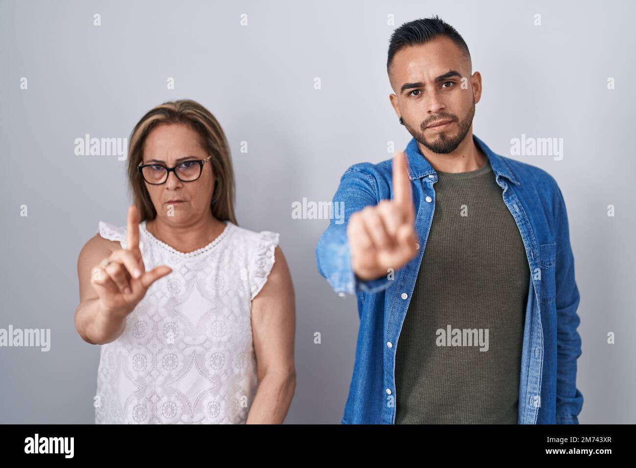 Hispanic mother and son standing together pointing with finger up and ...