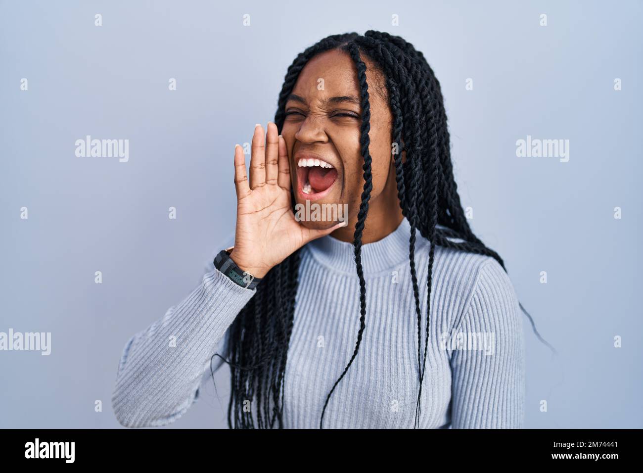 African american woman standing over blue background shouting and ...