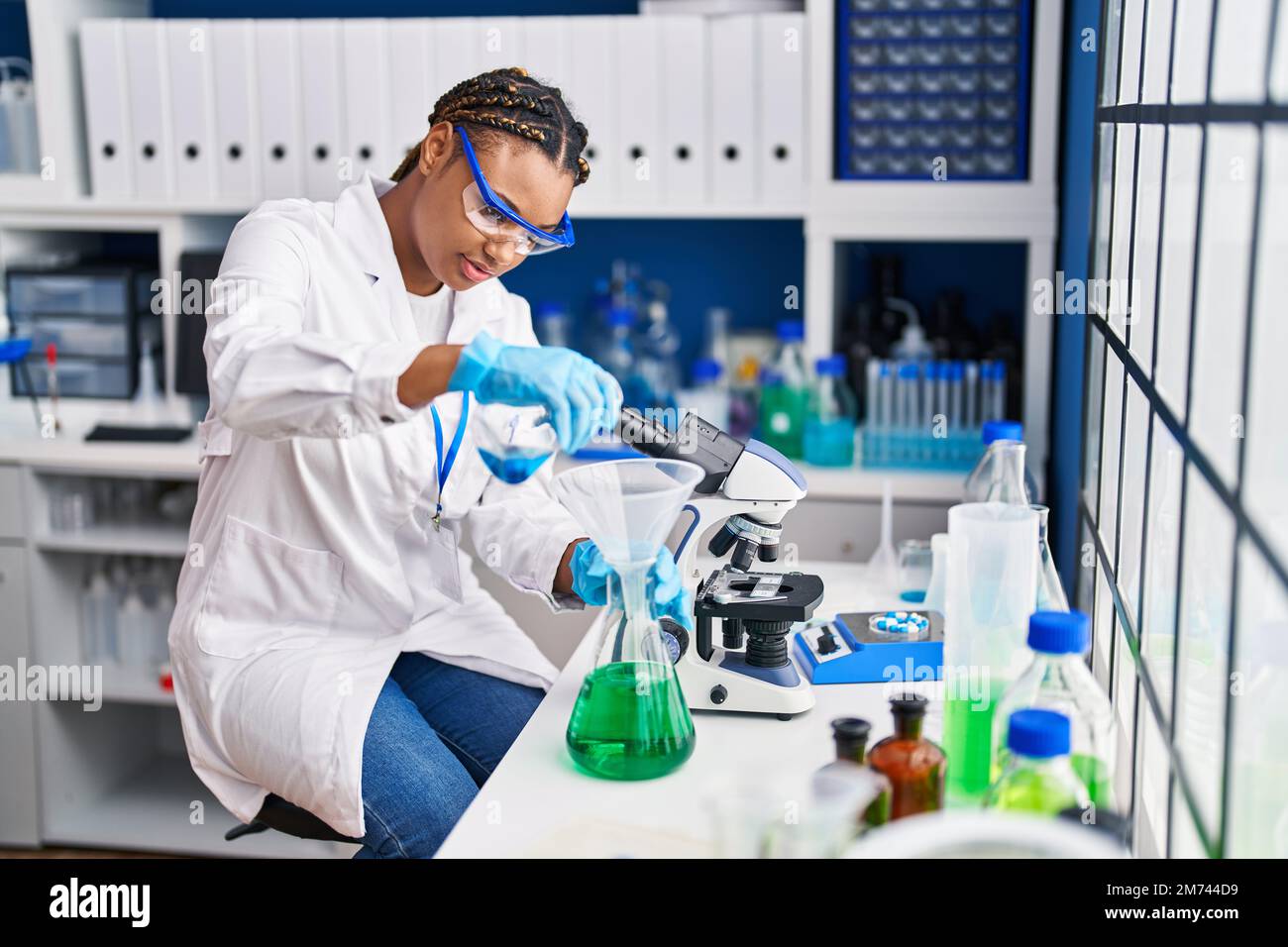 African american woman scientist pouring liquid on test tube at ...