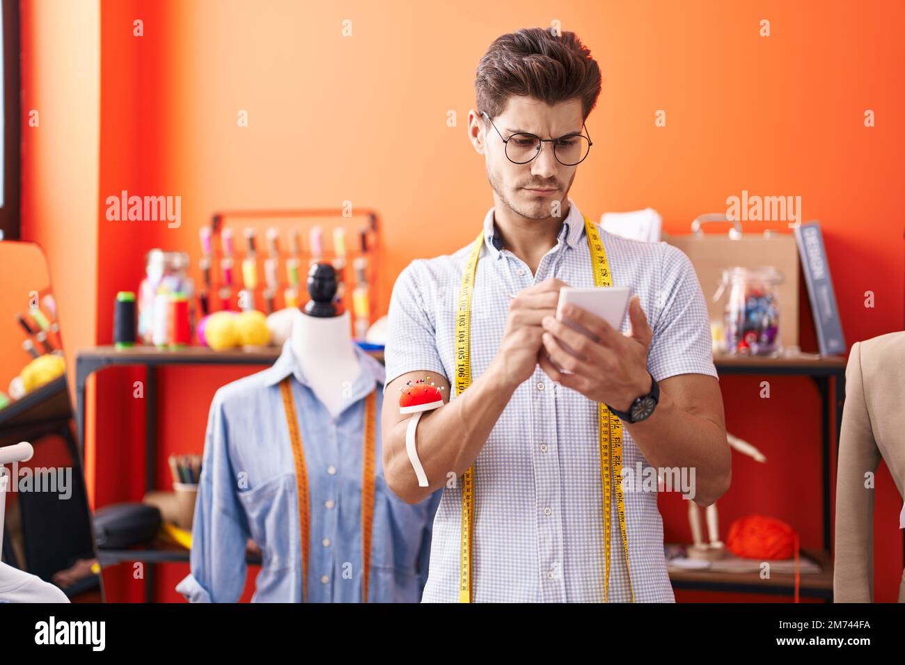 Young hispanic man tailor writing on notebook at atelier Stock Photo ...