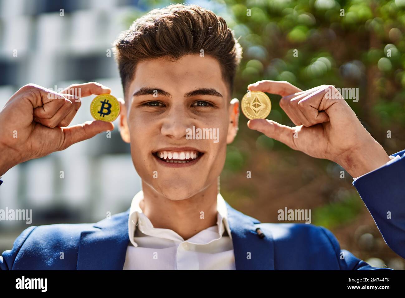 Young man smiling confident holding bitcoin and ethereum at park Stock ...