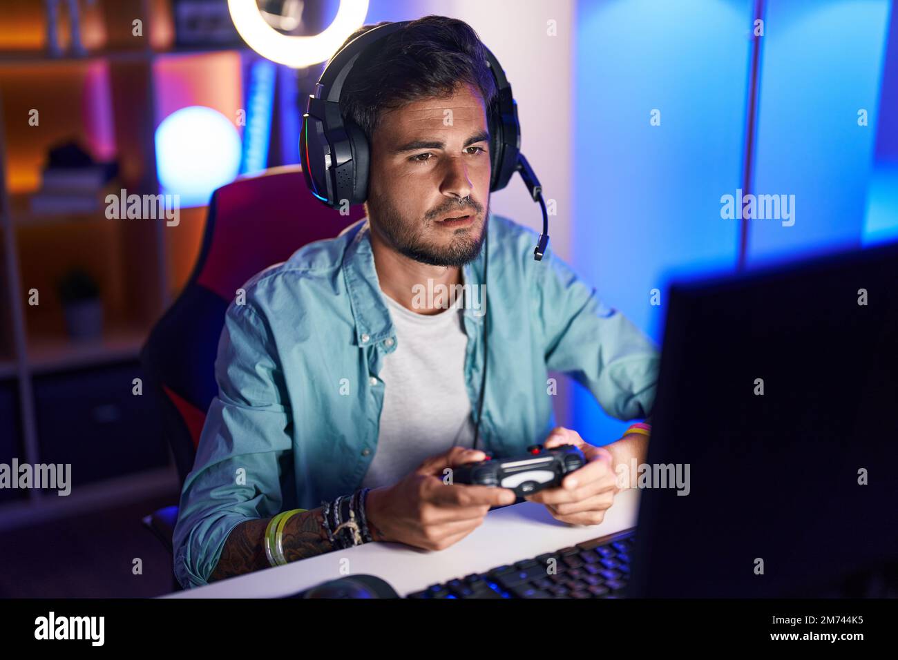Young hispanic man streamer playing video game using joystick at gaming ...