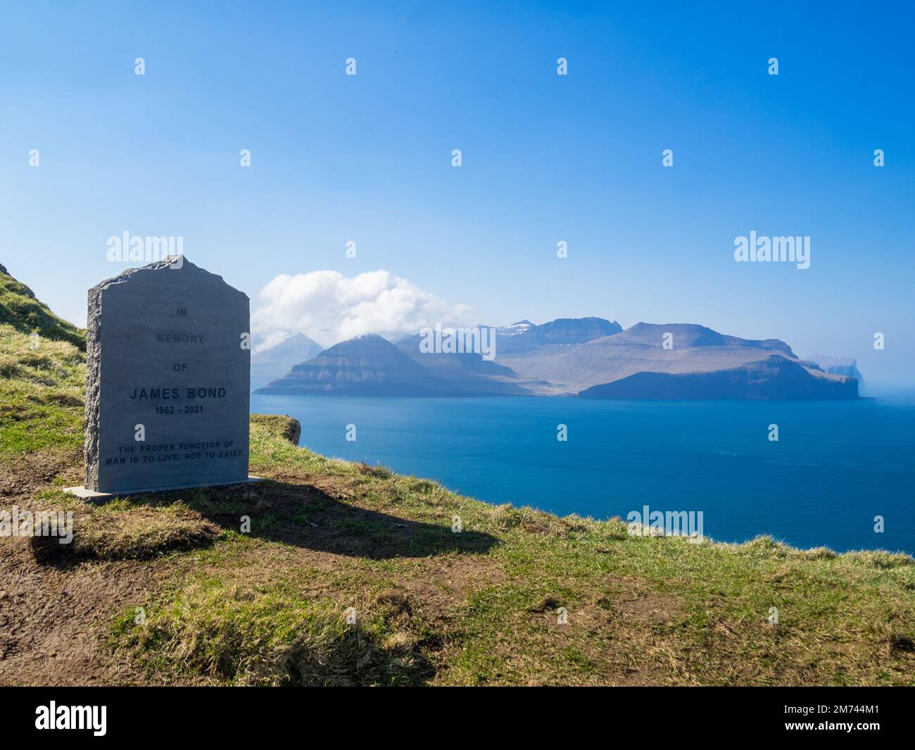 James Bon grave stone by the cliffs edge in Kalsoy island with Eysturoy ...