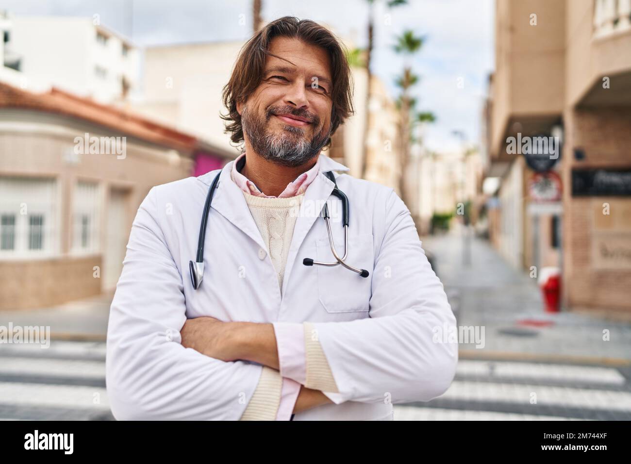 Middle age man doctor smiling confident standing with arms crossed ...