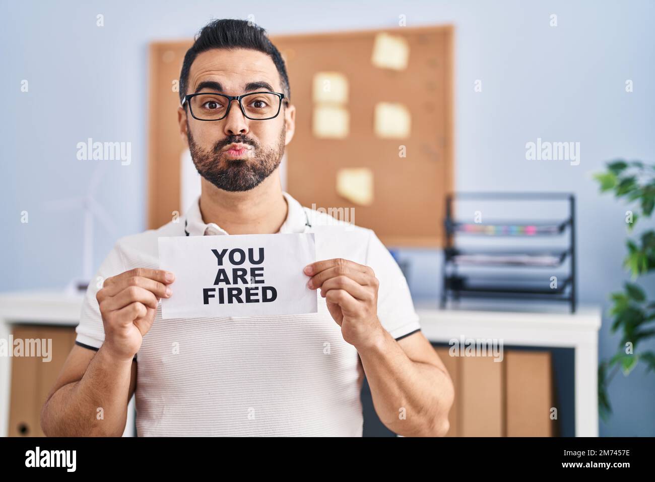 Young hispanic man with beard holding you are fired banner at the ...