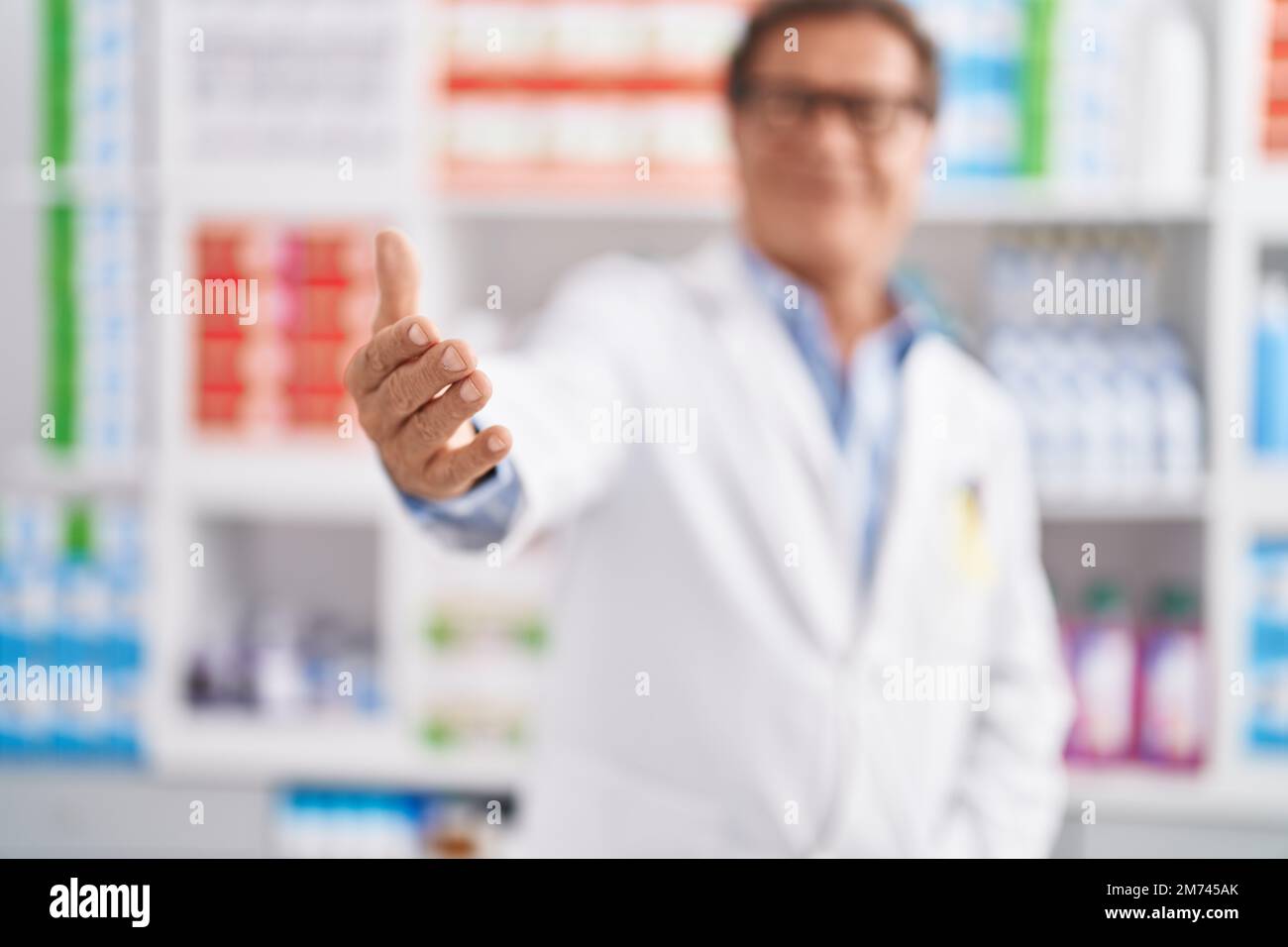 Middle age man pharmacist smiling confident shake hand at pharmacy ...