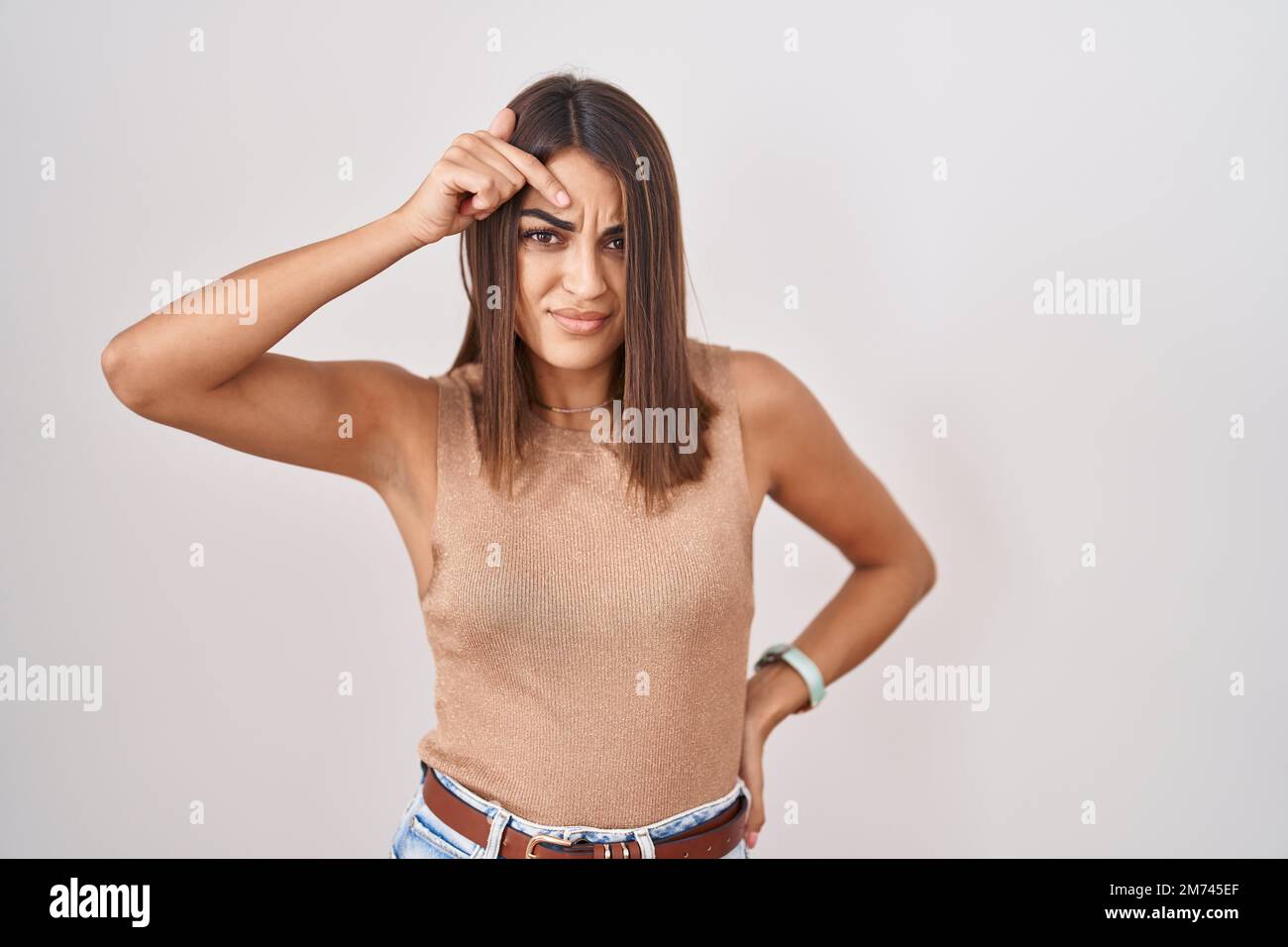 Young hispanic woman standing over white background pointing unhappy to ...