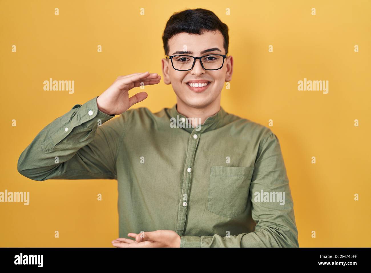 Non binary person standing over yellow background gesturing with hands ...