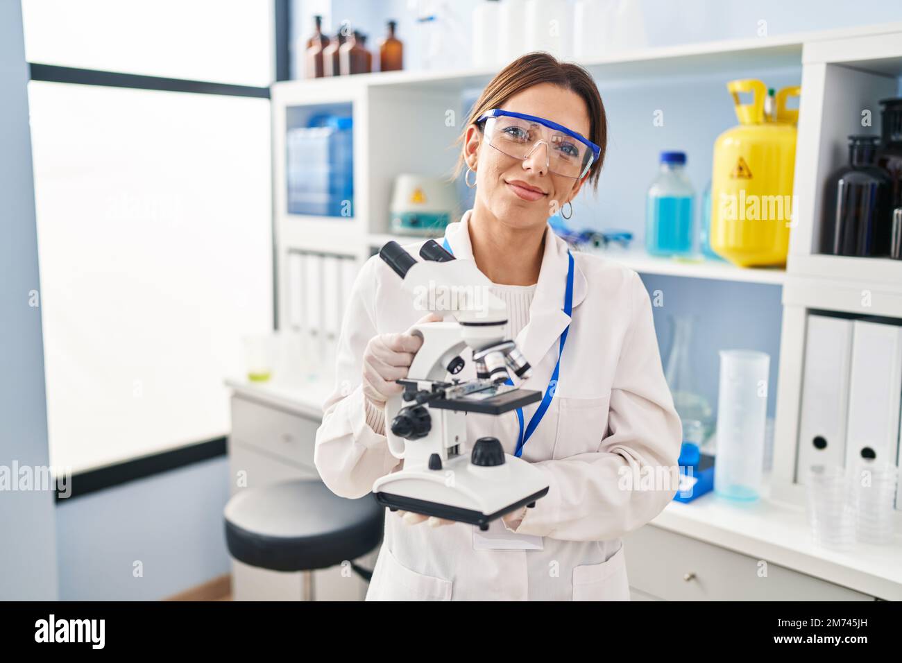 Young brunette woman working at scientist laboratory with microscope ...