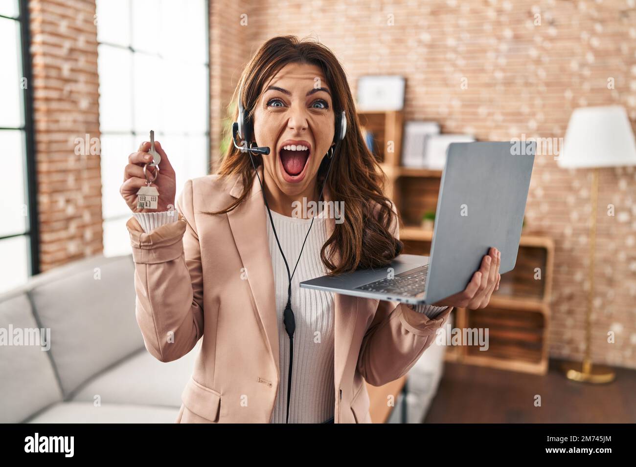 Young brunette woman working as real state agent holding keys of new ...