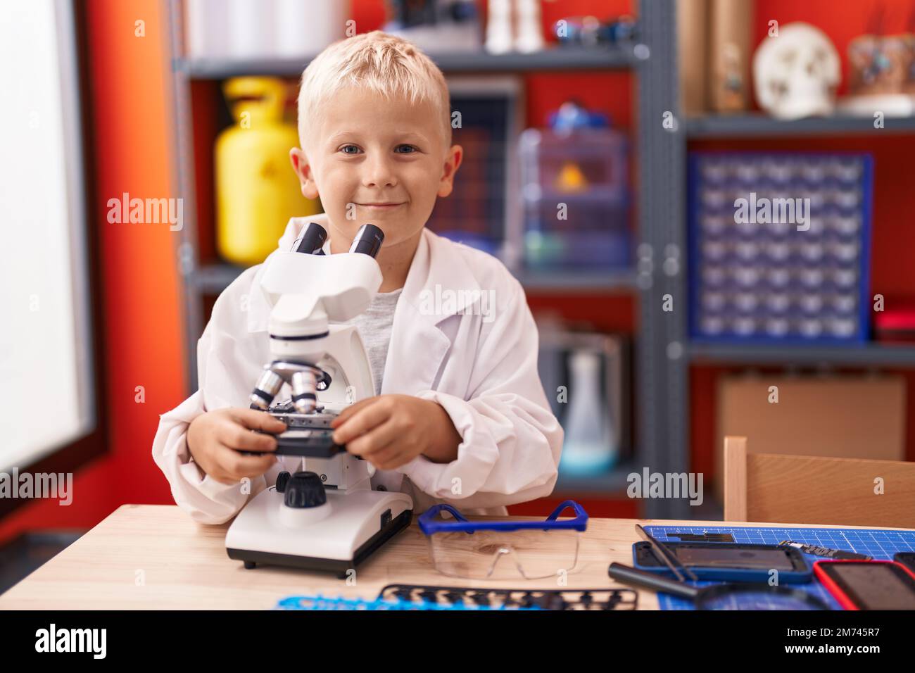 Adorable toddler student using microscope standing at classroom Stock ...