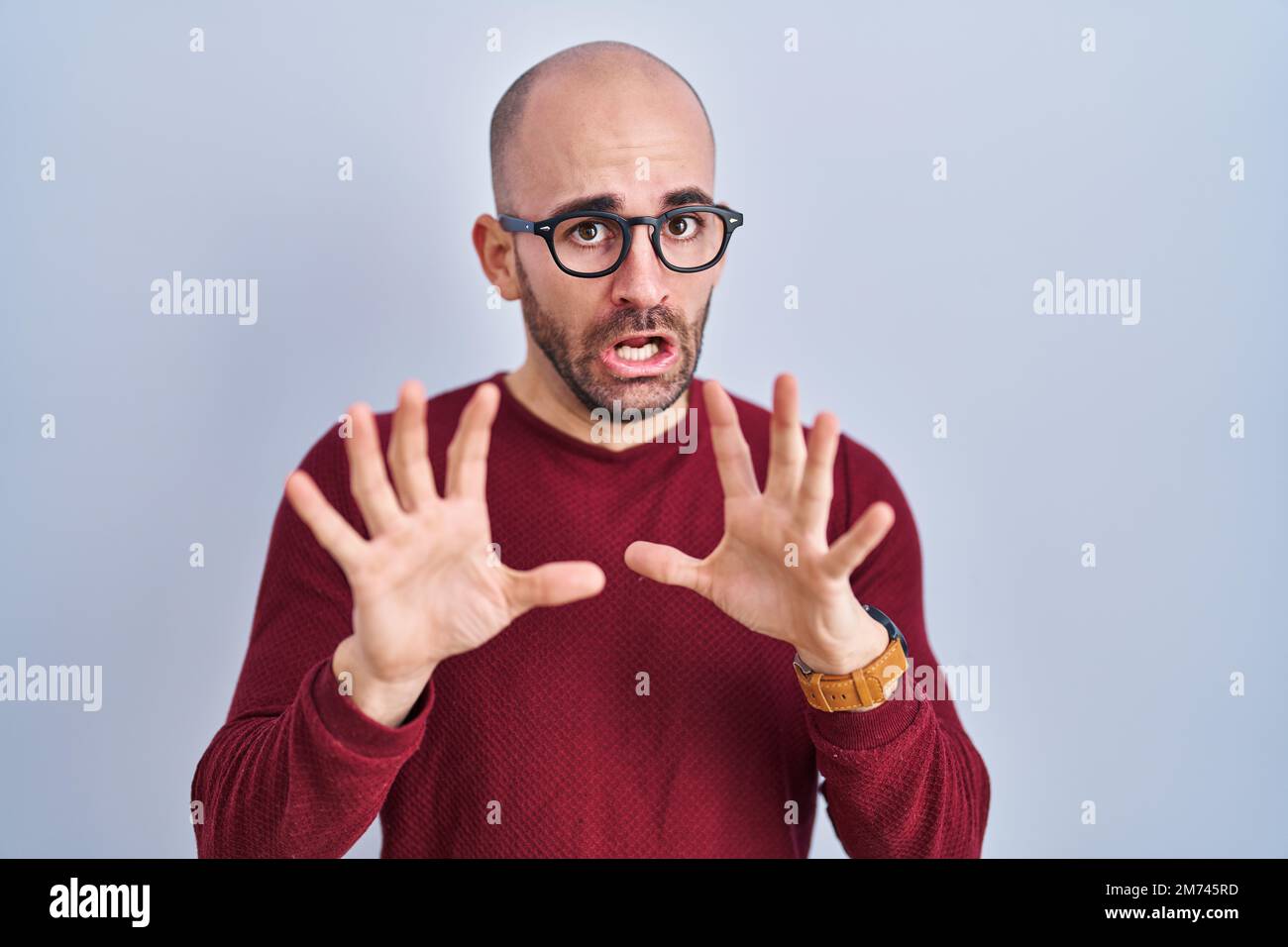 Young bald man with beard standing over white background wearing ...