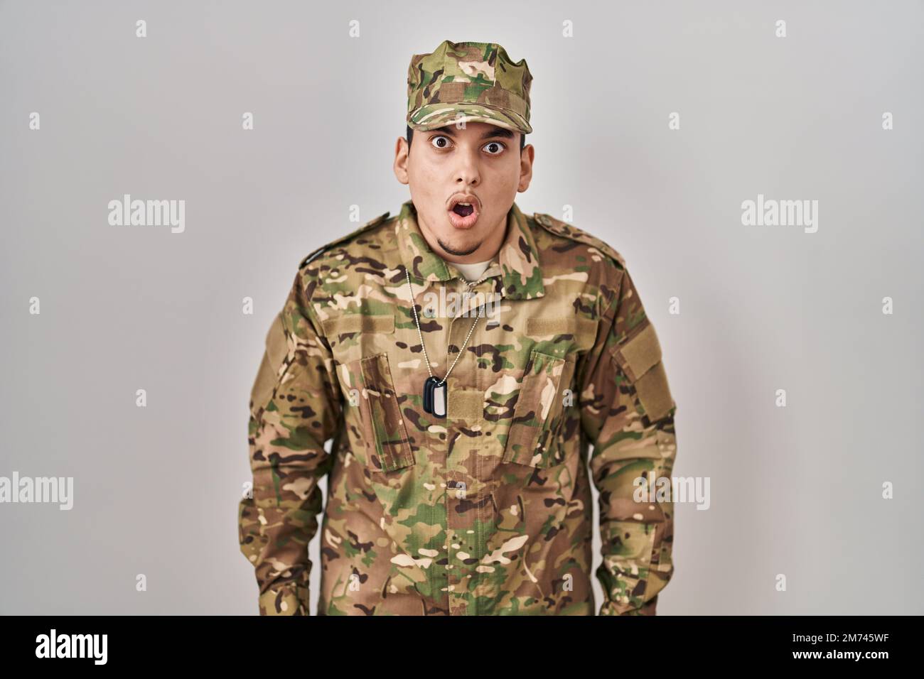 Young arab man wearing camouflage army uniform afraid and shocked with ...