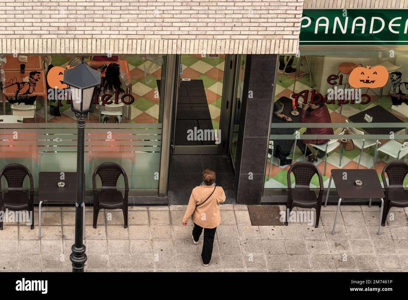 aerial view of a lady dressed in a beige coat on the street to enter a ...