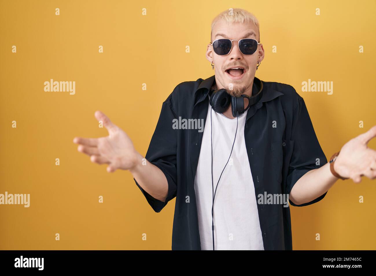 Young caucasian man wearing sunglasses standing over yellow background ...