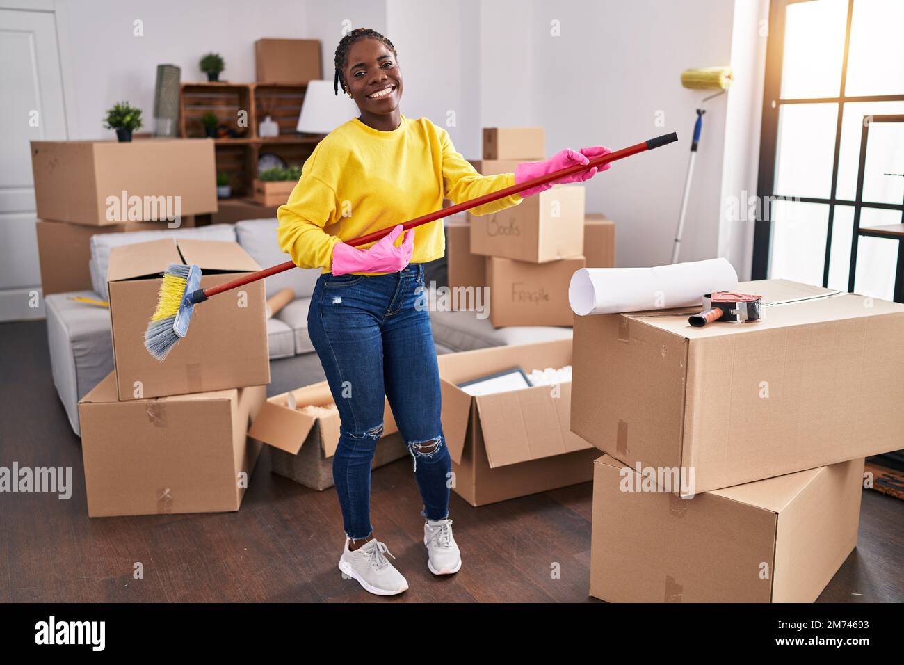 African american woman playing mop as a guitar cleaning at new home ...