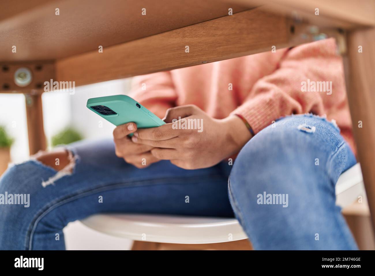 Young hispanic woman using smartphone under table at home Stock Photo ...