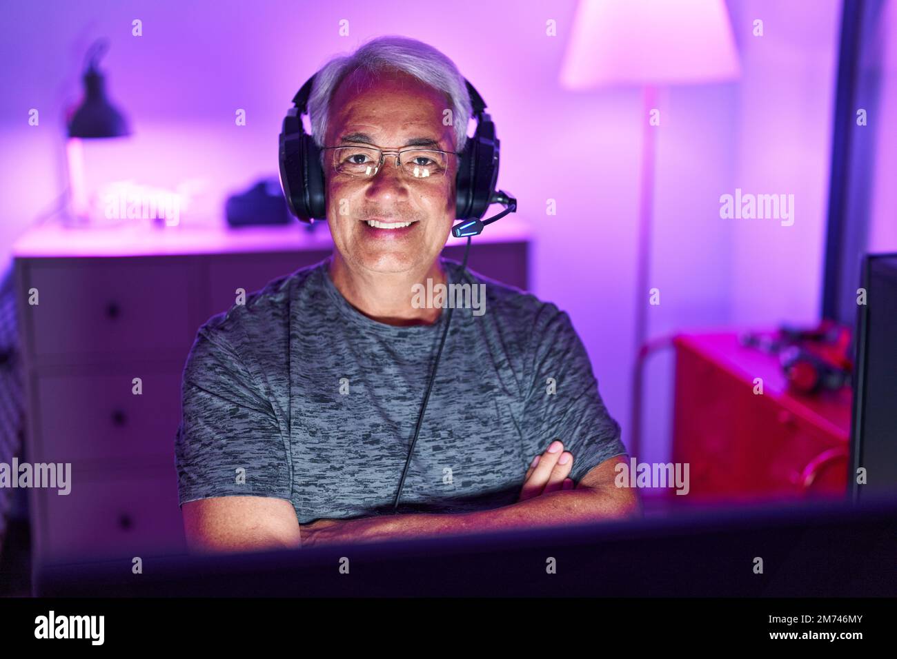 Middle age grey-haired man streamer smiling confident sitting with arms ...