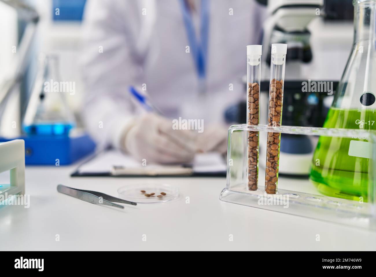 Young hispanic man scientist writing on document at laboratory Stock ...