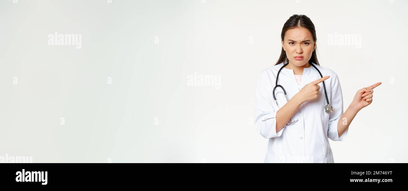 Angry female doctor, asian physician in medical robe and stethoscope ...