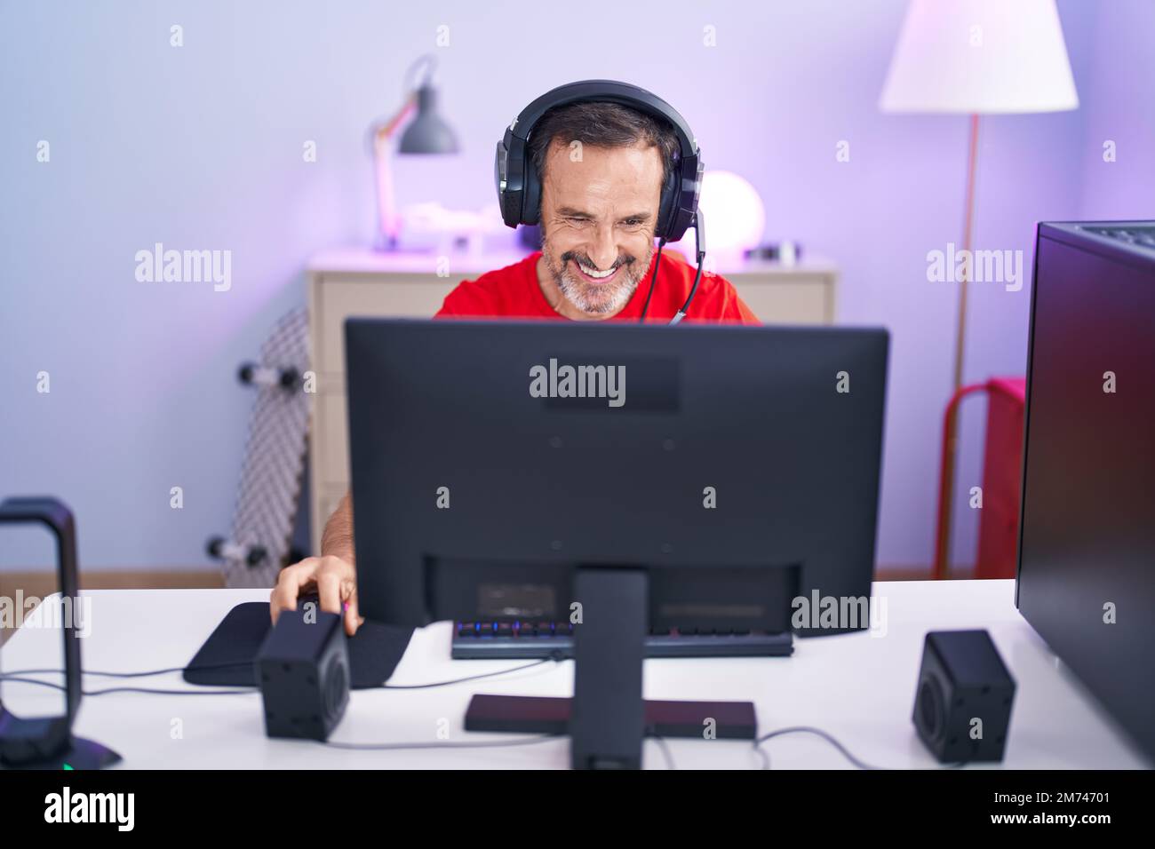 Middle age man streamer playing video game using computer at gaming ...