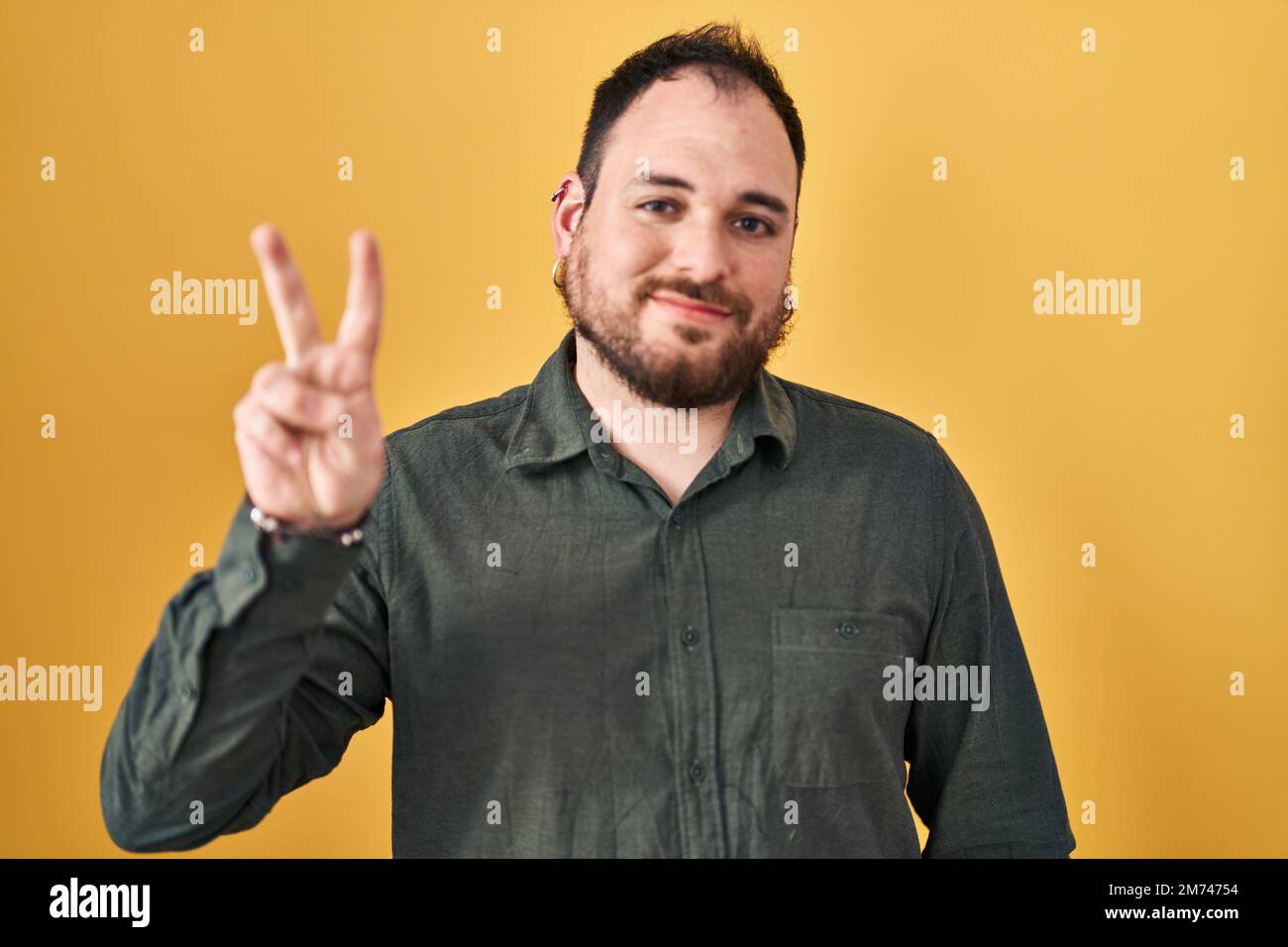 Plus size hispanic man with beard standing over yellow background ...