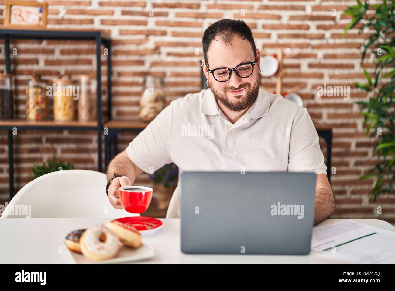 Young hispanic man using laptop drinking coffee at home Stock Photo - Alamy