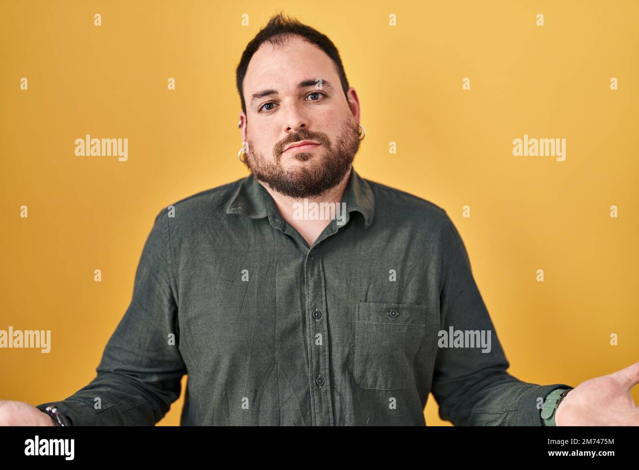 Plus size hispanic man with beard standing over yellow background ...
