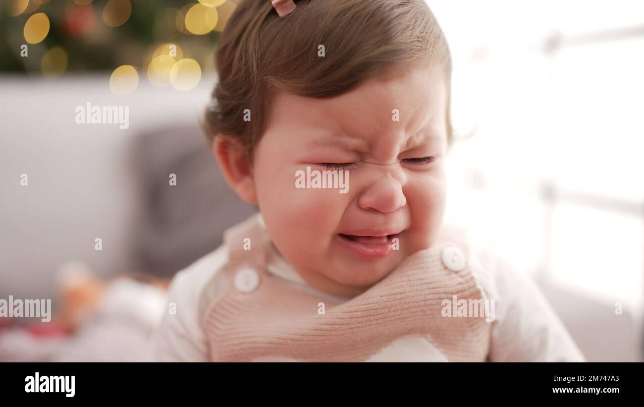 Adorable toddler standing by christmas tree crying at home Stock Photo ...