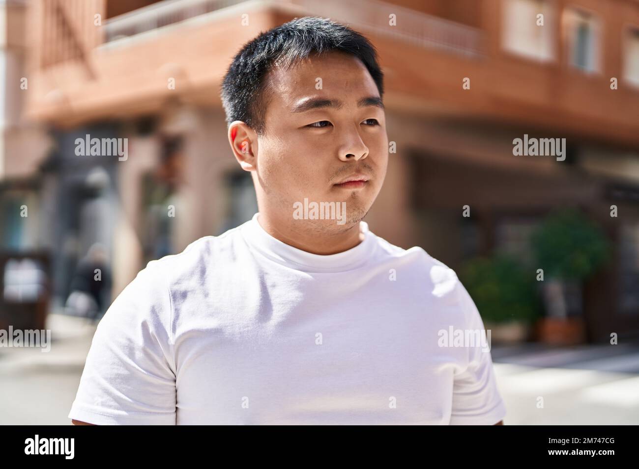 Young chinese man standing with relaxed expression at street Stock ...