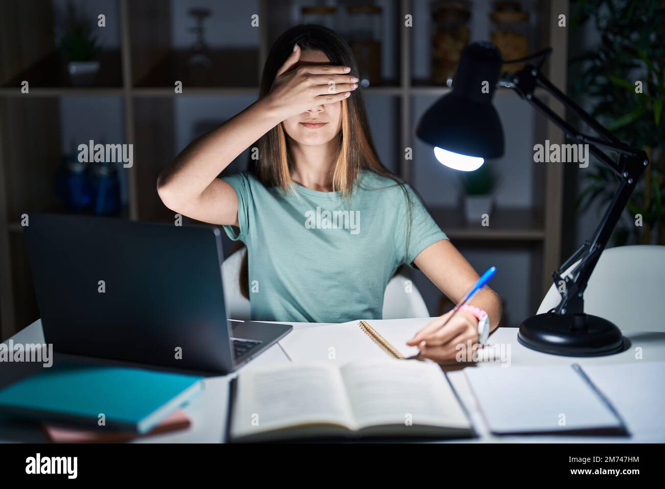 Teenager girl doing homework at home late at night smiling and laughing ...