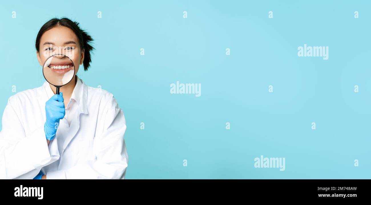 Funny asian female physician, doctor showing her smile with magnifying ...