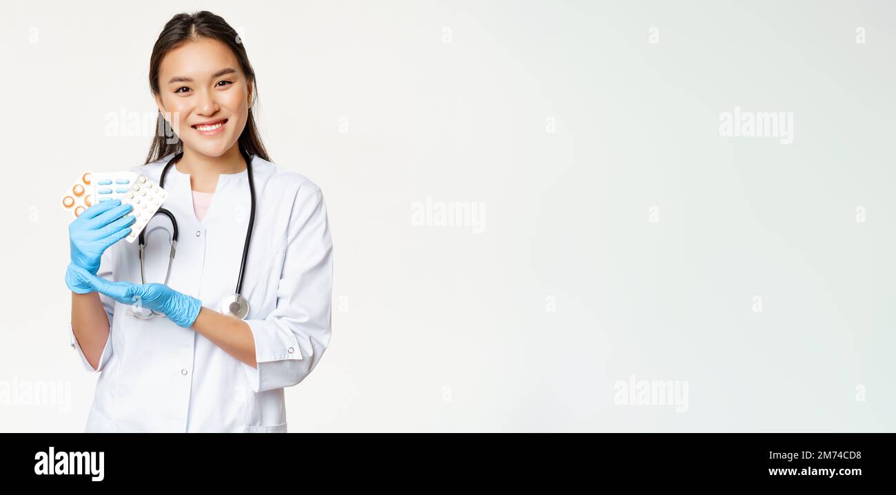 Smiling asian woman doctor demonstrating pills, vitamins, advertising ...